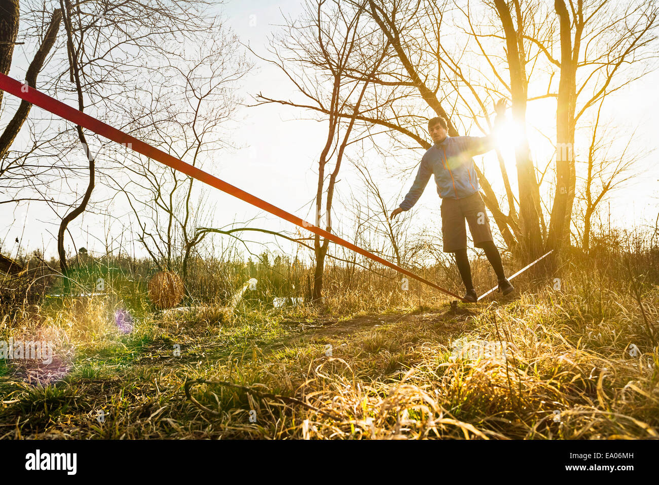 Young man balancing on one leg on slackline in field landscape Stock ...