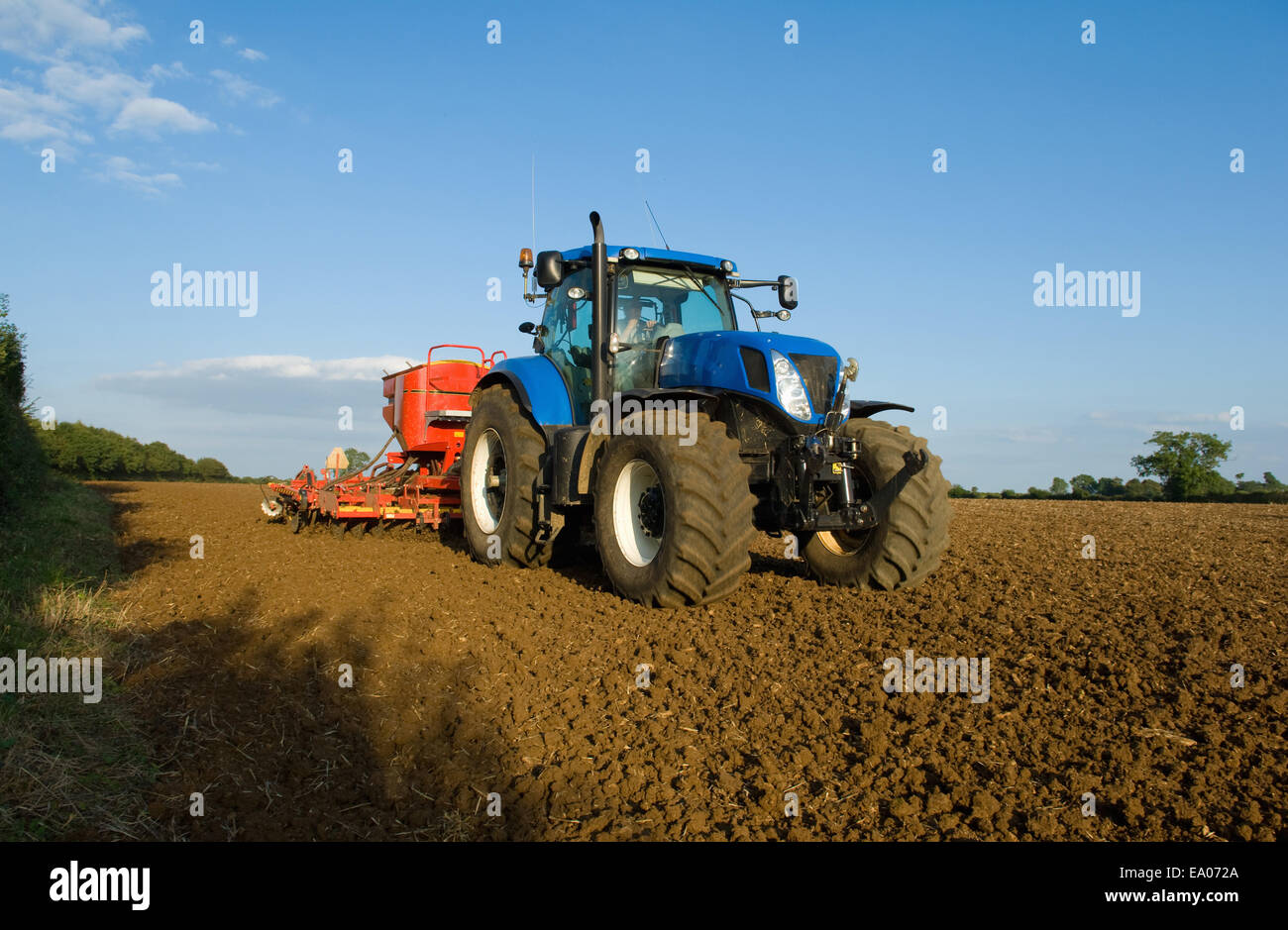 Farmer driving tractor and drilling seed corn in ploughed field Stock ...