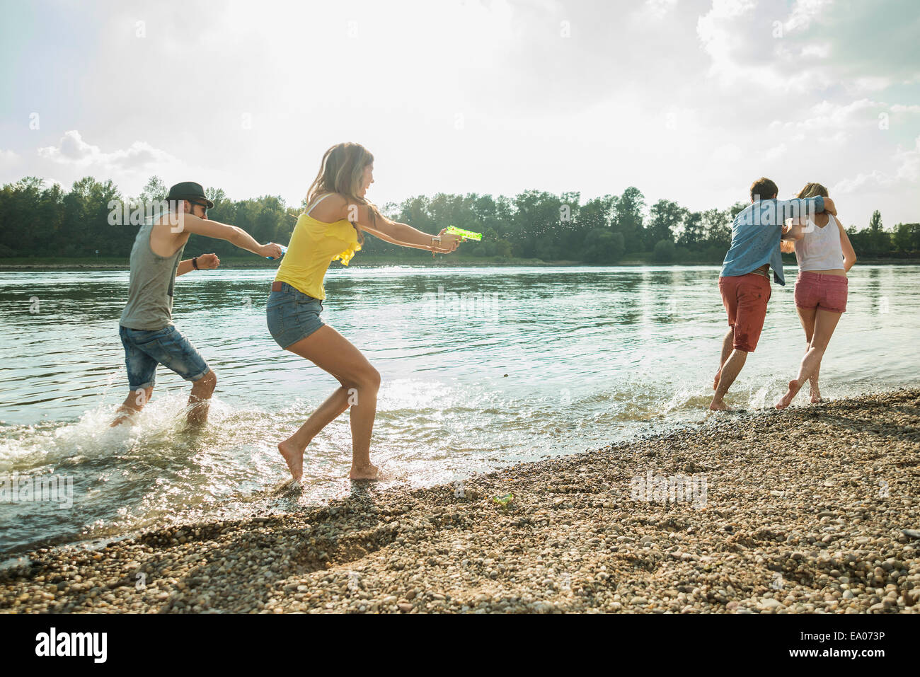 Friends playing with water pistols in lake Stock Photo - Alamy