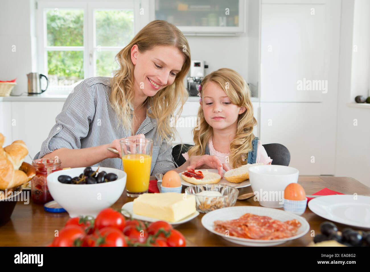 Mother and daughter eating at kitchen table Stock Photo - Alamy