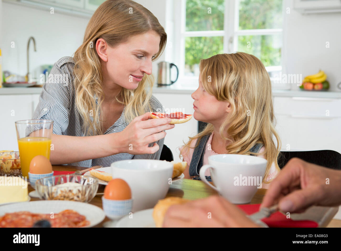 Mother offering daughter some food Stock Photo - Alamy