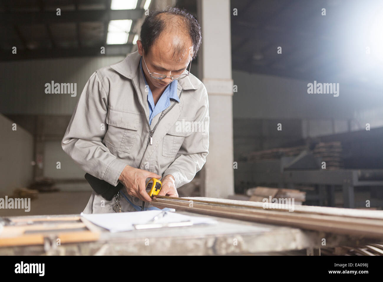 Carpenter measuring wood plank with tape measure in factory, Jiangsu ...