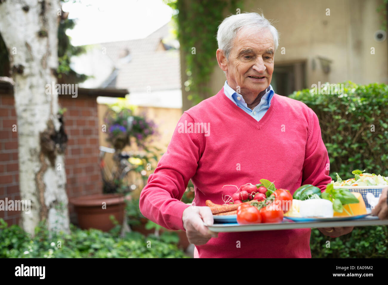 Senior man carrying tray of fresh food Stock Photo - Alamy