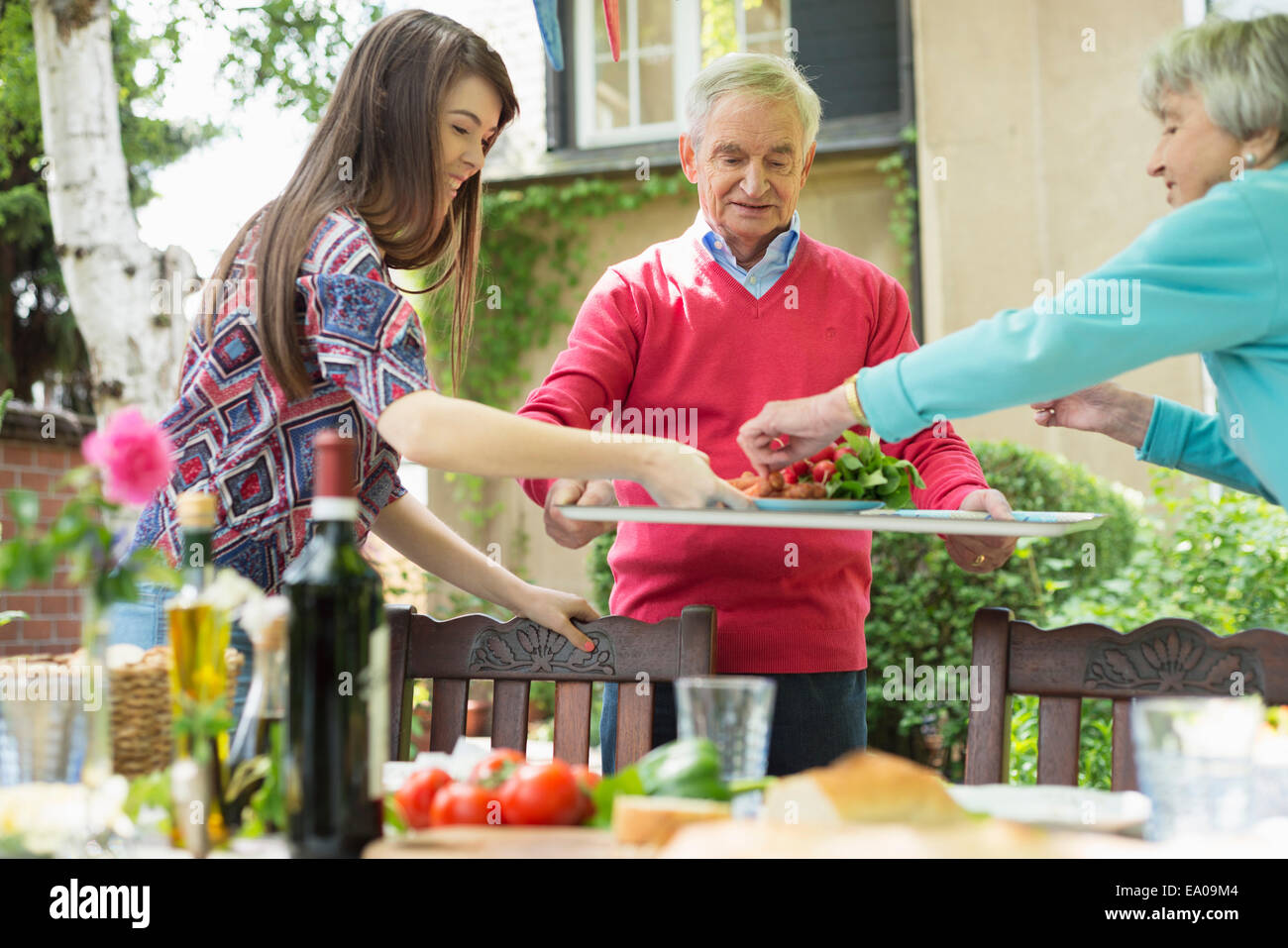 Young woman with grandparents setting the table Stock Photo - Alamy