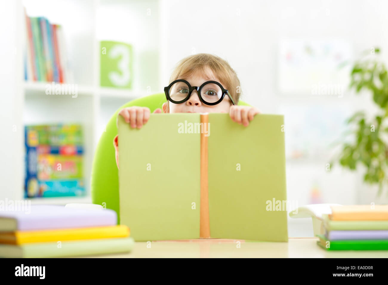 clever kid little girl behind of open book indoor Stock Photo - Alamy