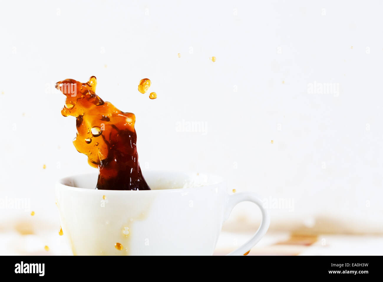 Cup of spilling coffee creating beautiful splash with stains on white ...