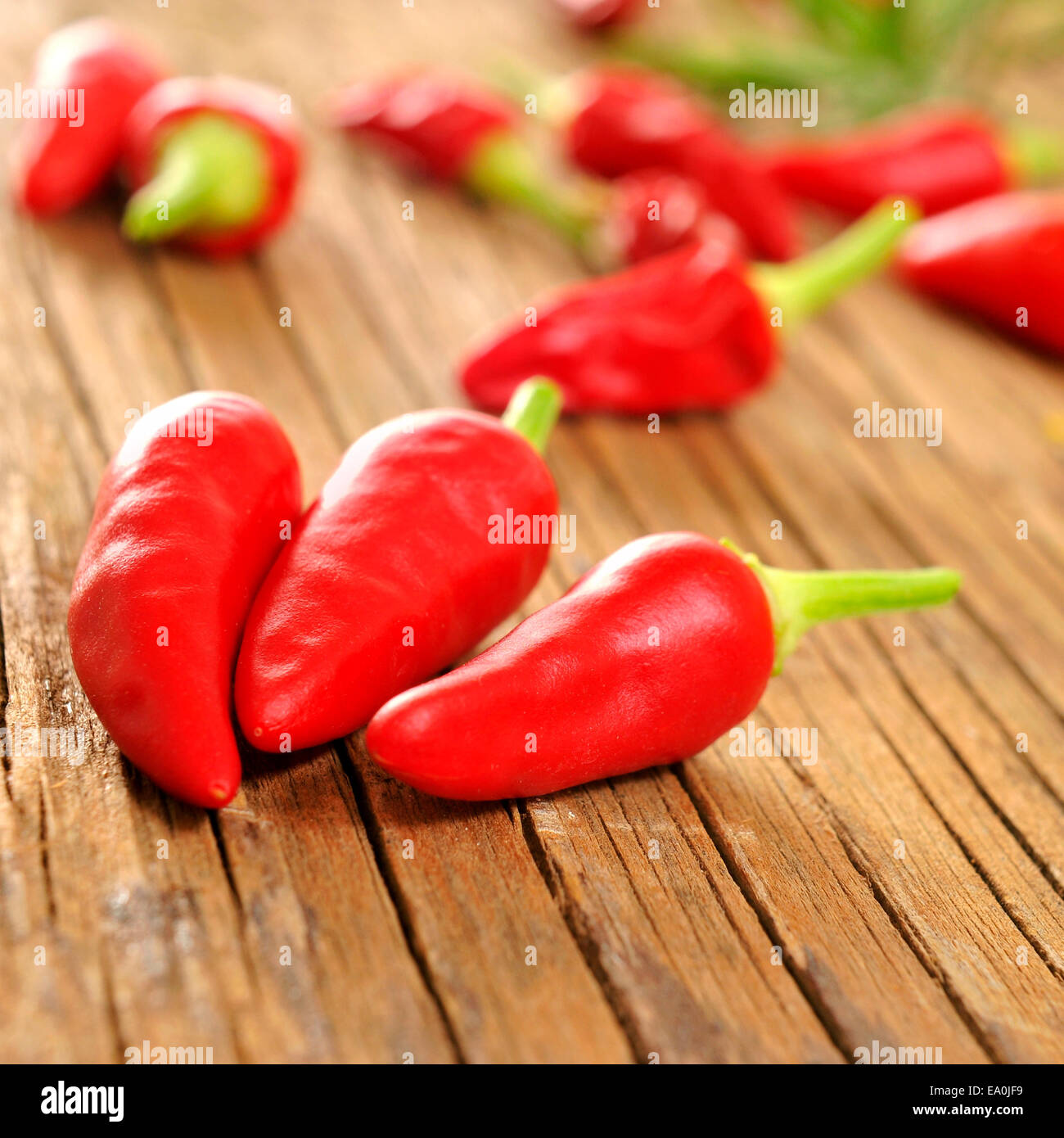 some small red peppers on a rustic wooden table Stock Photo - Alamy