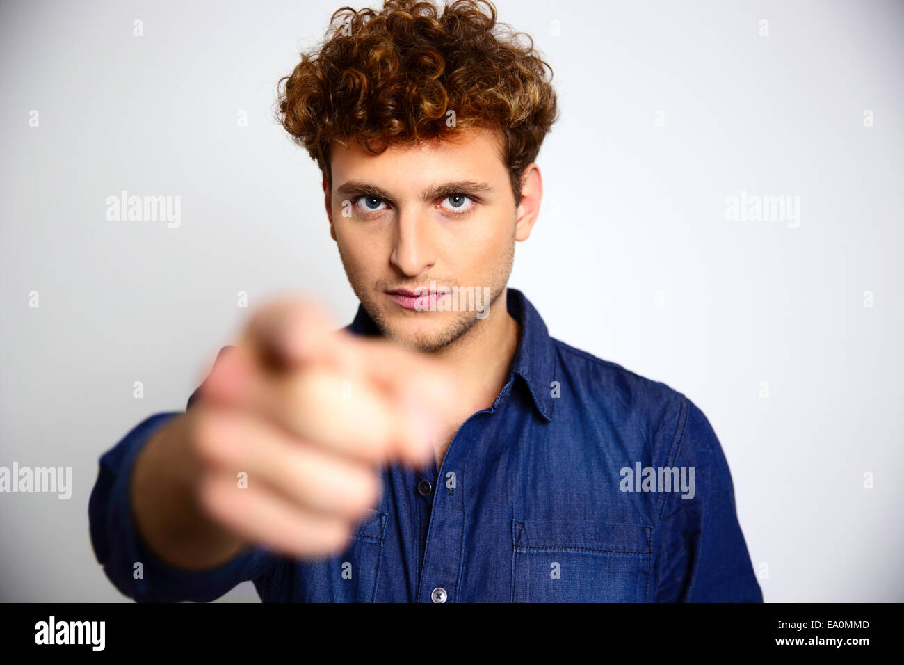 Serious man pointing on the camera over gray background Stock Photo - Alamy