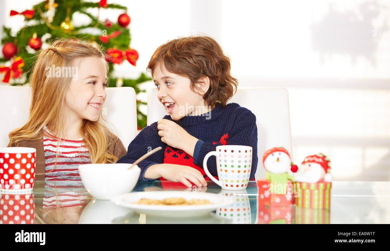 Two happy children eating cookies at christmas at the table Stock Photo ...
