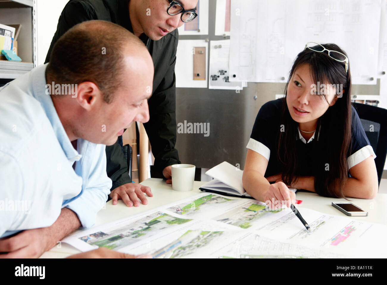 Team of three architects discussing ideas for blueprint in office Stock ...