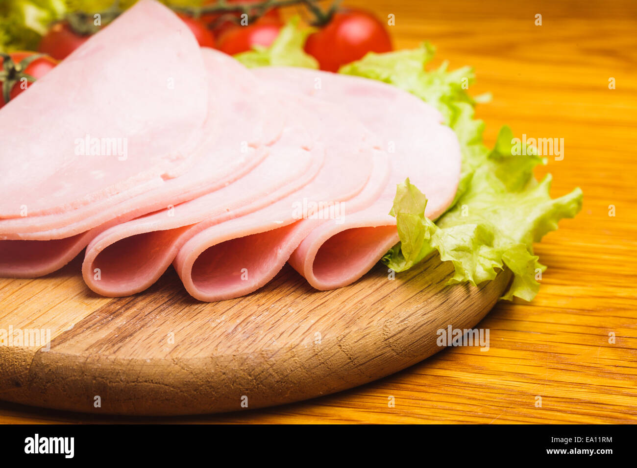 Fresh ham slices with lattuce and cherry tomato on the wooden board ...