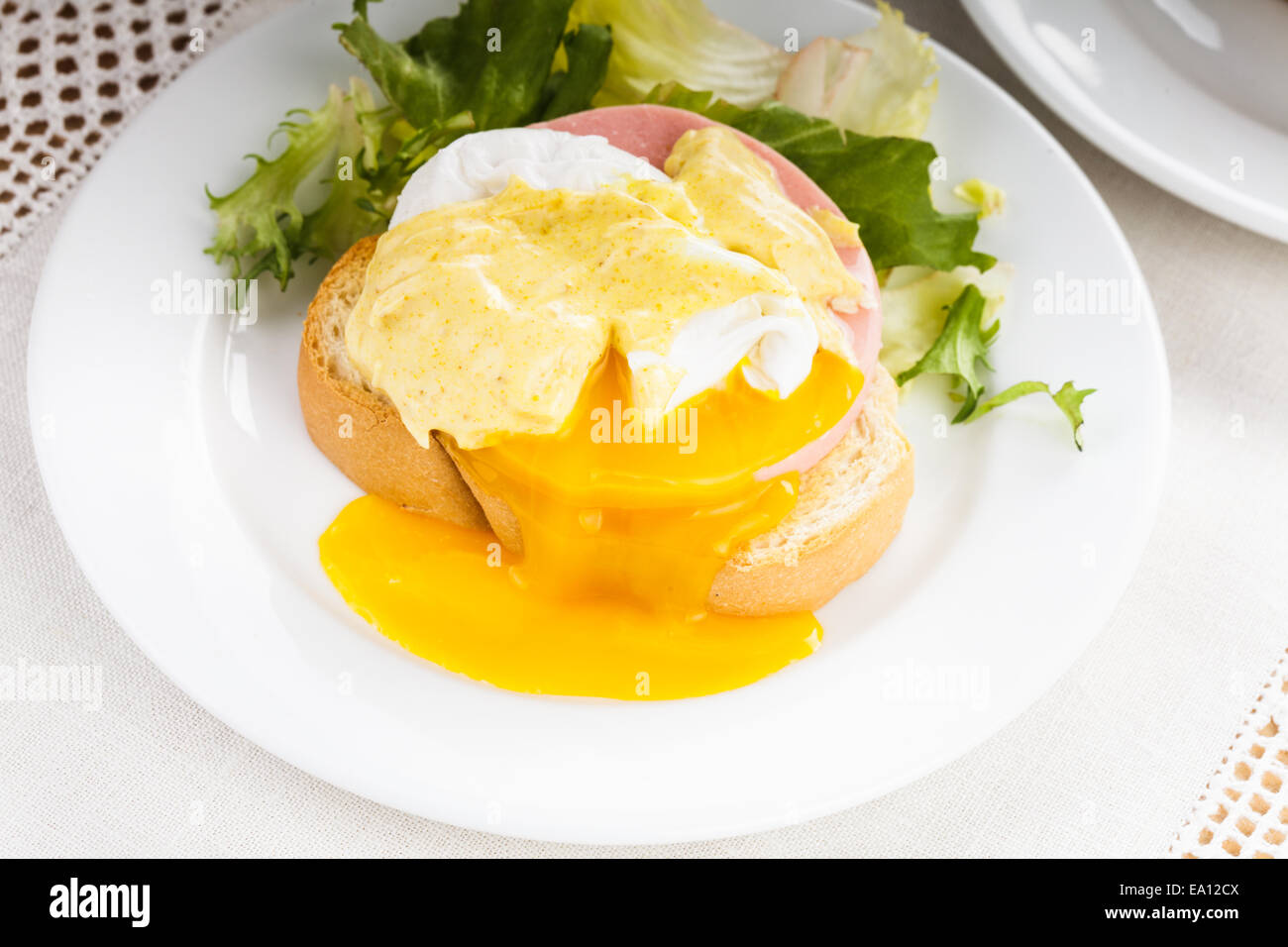 Eggs benedict close up on white plate, serving table Stock Photo - Alamy