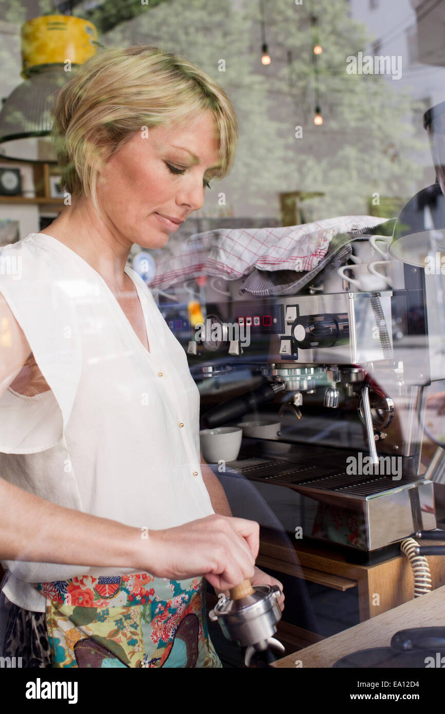 Mid adult woman making coffee in cafe Stock Photo - Alamy