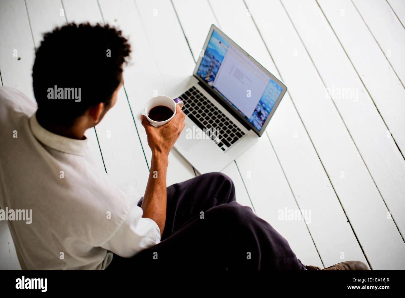 Graphic designer using laptop on floor Stock Photo - Alamy