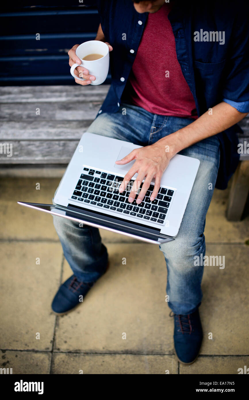 Man using laptop on bench Stock Photo - Alamy
