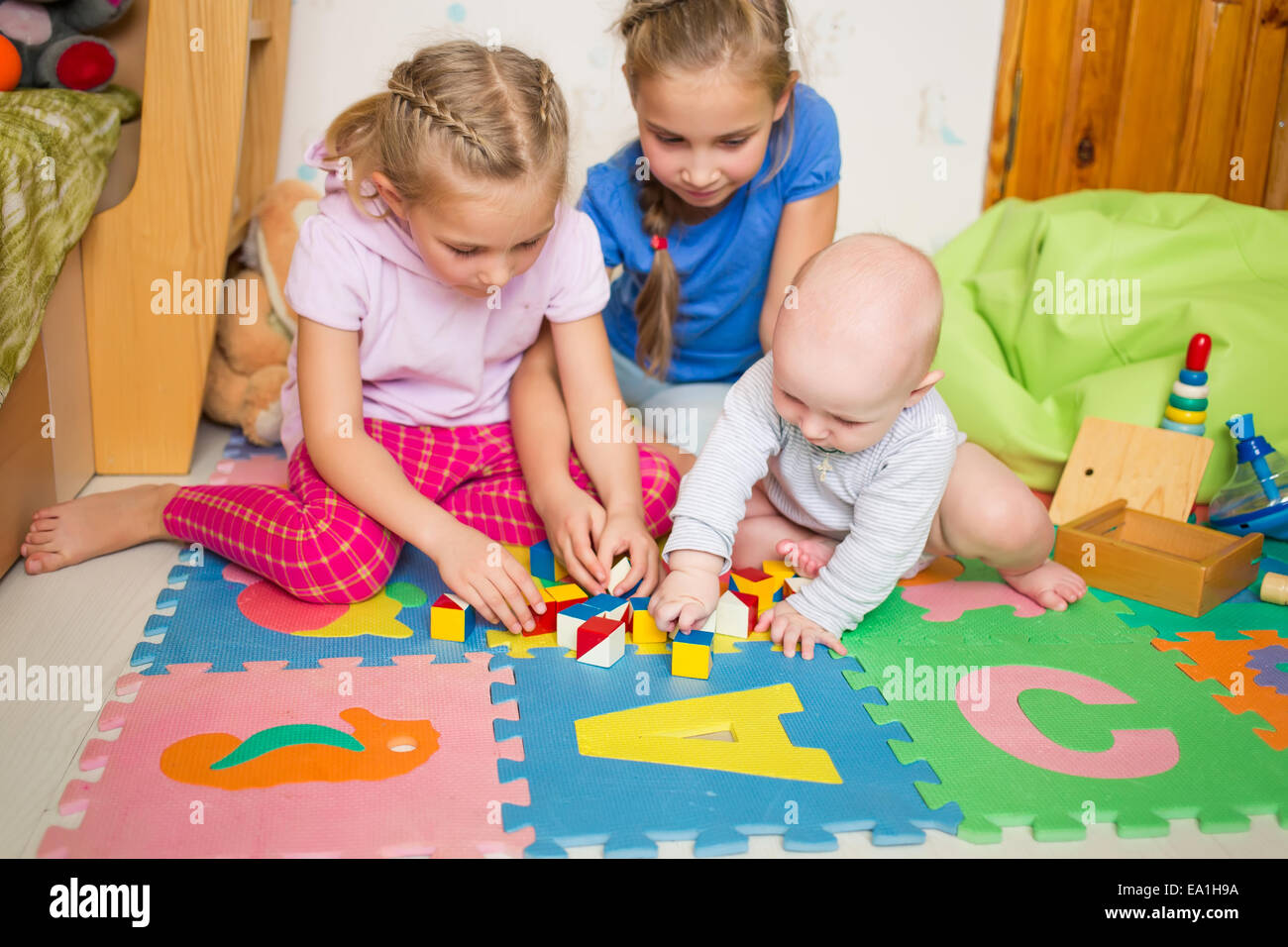 Happy kids playing with little brother in the room Stock Photo - Alamy