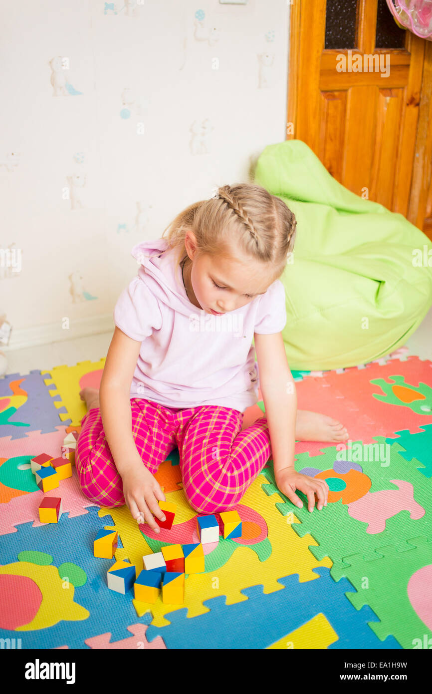Happy little girl playing with blocks in the room Stock Photo - Alamy