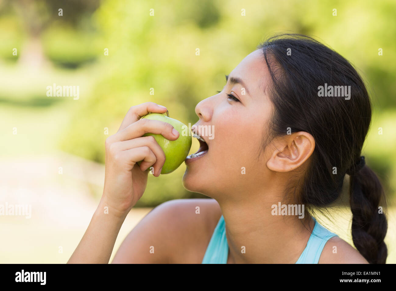 Healthy young woman eating apple in park Stock Photo - Alamy