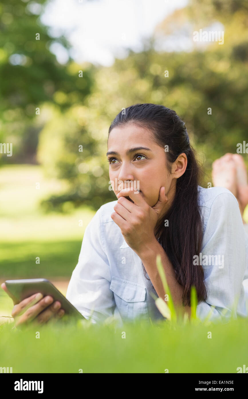 Thoughtful woman text messaging in park Stock Photo - Alamy