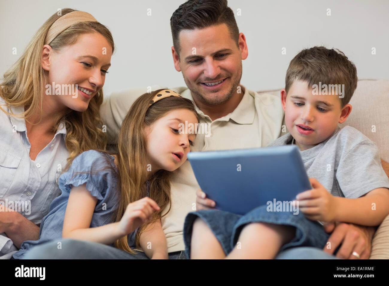 Family using digital tablet together on sofa Stock Photo - Alamy