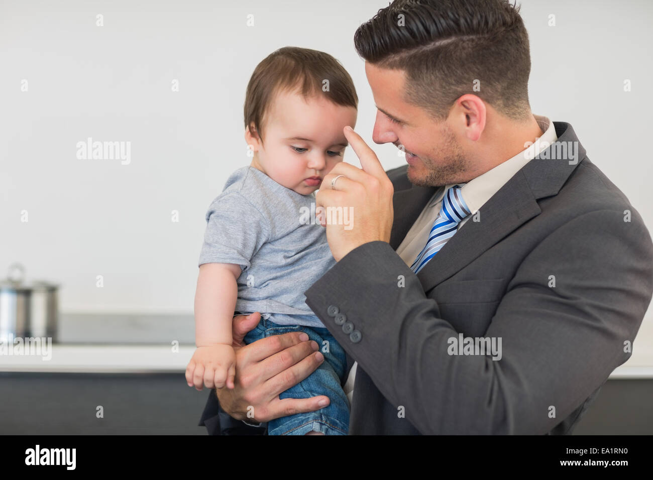 Businessman carrying baby boy in kitchen Stock Photo - Alamy