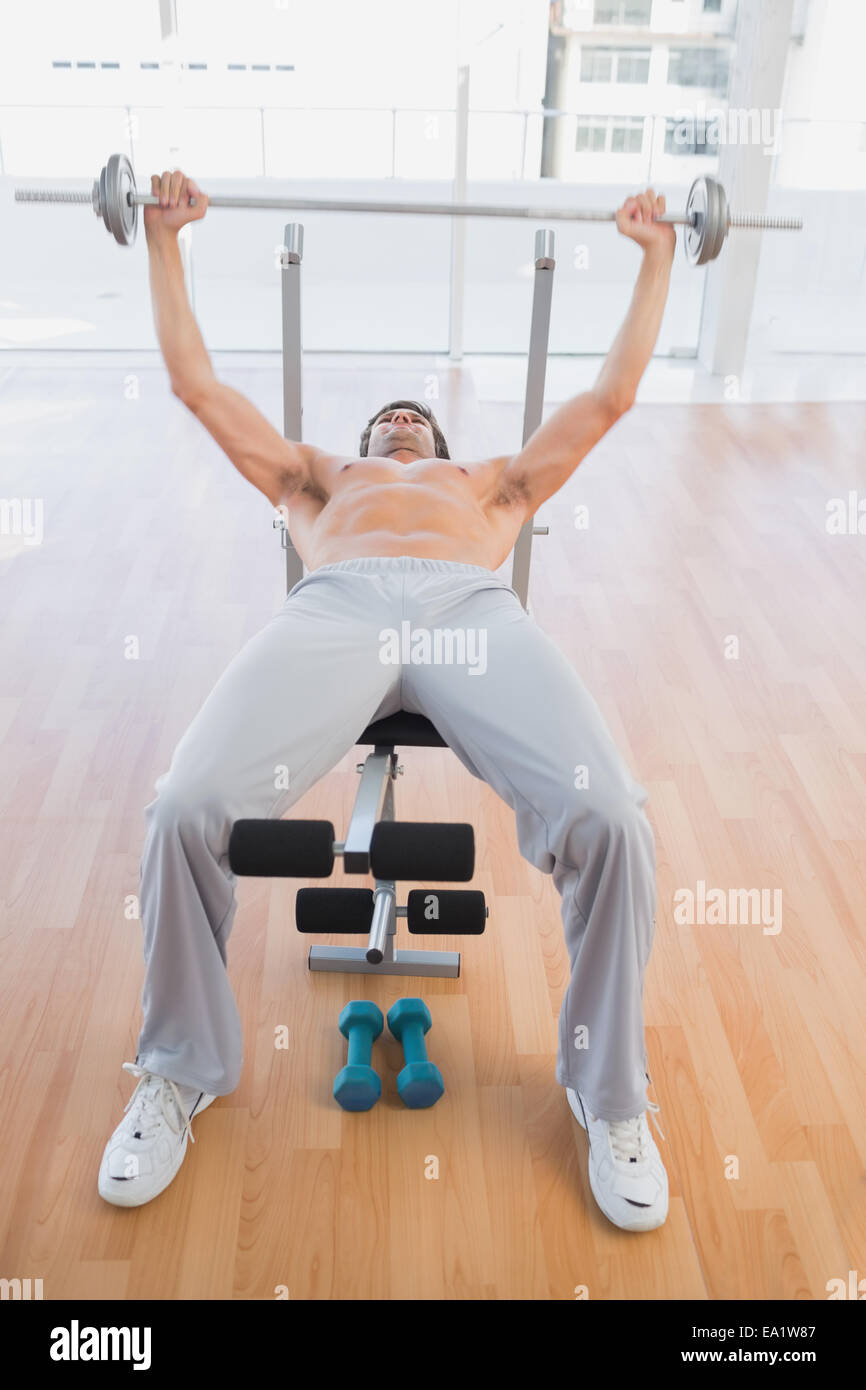 Fit man lifting barbell bench press in gym Stock Photo - Alamy
