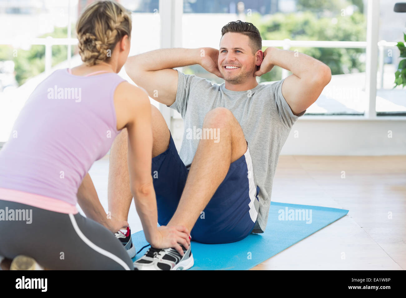 Trainer helping fit man in doing sits up Stock Photo - Alamy