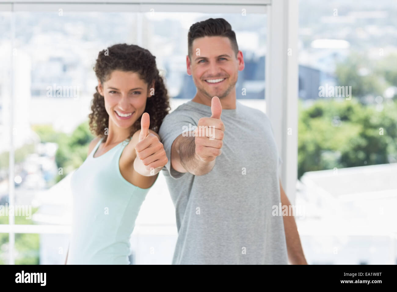 Couple gesturing thumbs up in exercise room Stock Photo - Alamy