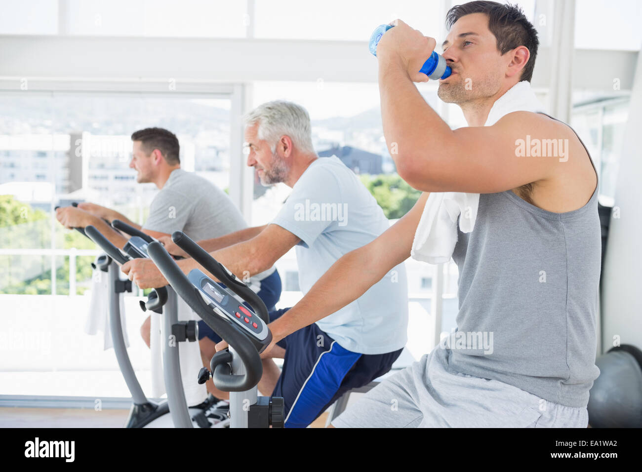 Man on exercise bike drinking water Stock Photo - Alamy