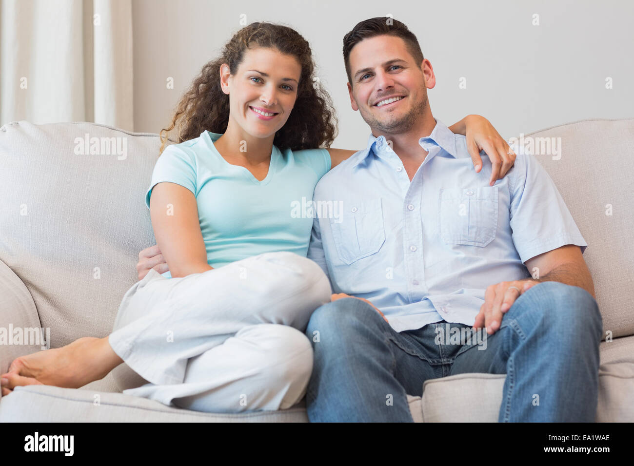 Happy couple sitting on sofa Stock Photo - Alamy