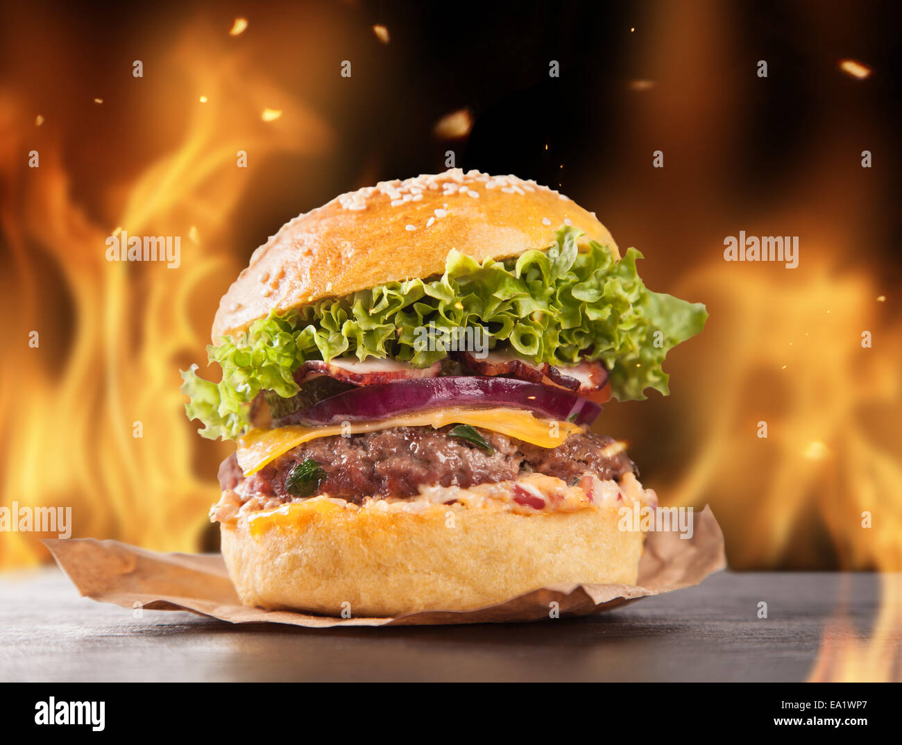 Fresh home-made hamburgers served on black stone. Fire flames around ...
