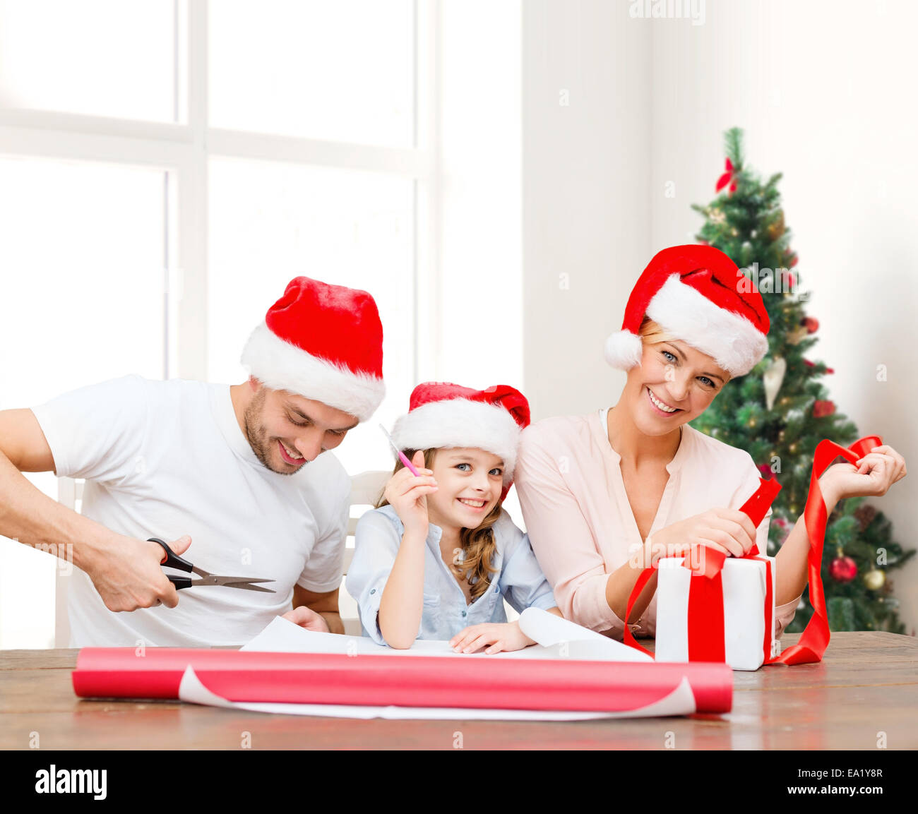 happy family in santa helper hats packing gift Stock Photo - Alamy