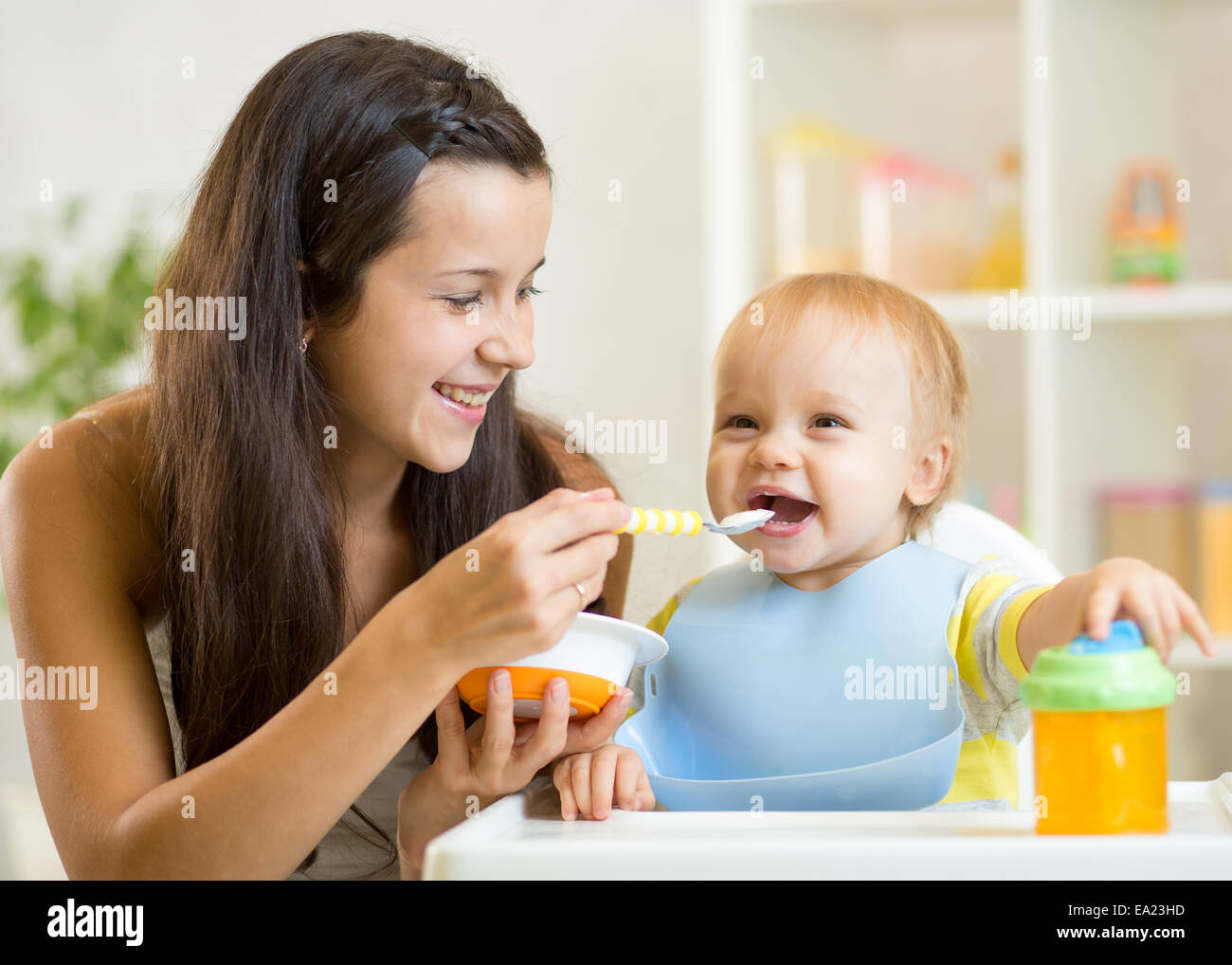 Happy mother spoon feeding her baby child Stock Photo - Alamy