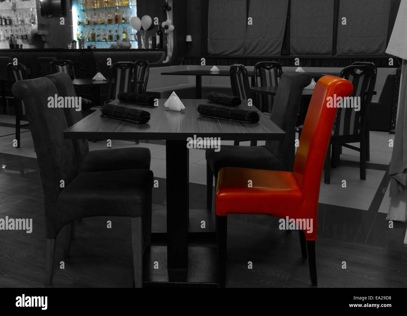 Greyscale restaurant interior with a single red chair in selective ...