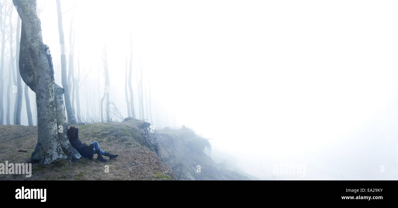 Emotions conceptual image. Sad and lonely person sitting in dark forest ...