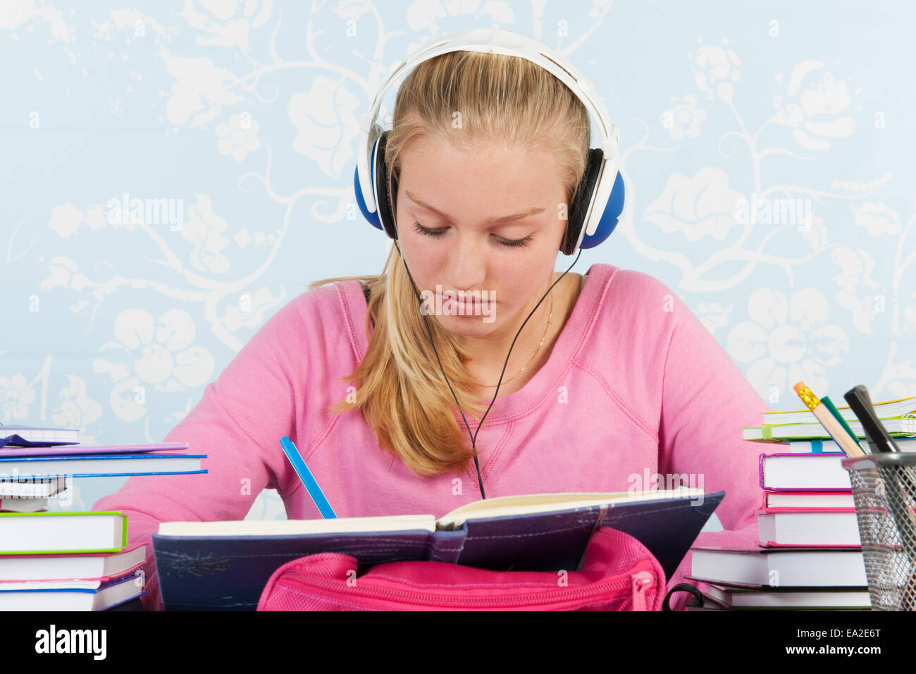 High school student making homework at desk with music on headphones ...