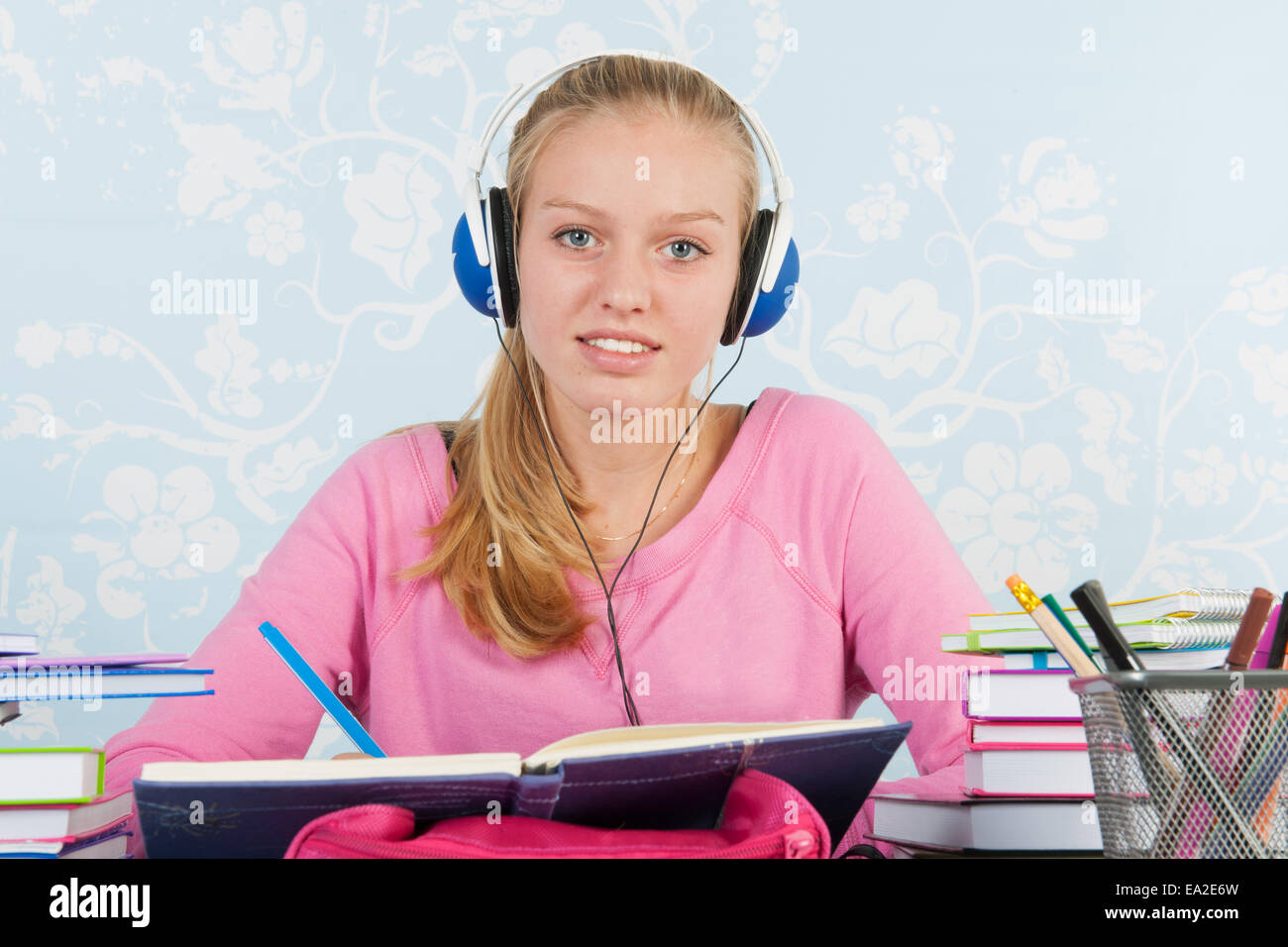 High school student making homework at desk with music on headphones ...