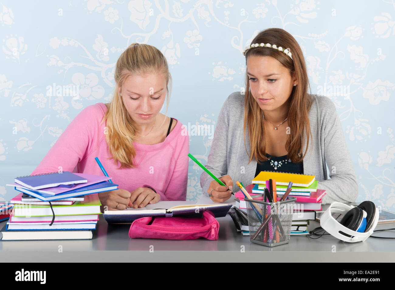 two teengirls sitting at desk making homework together Stock Photo - Alamy