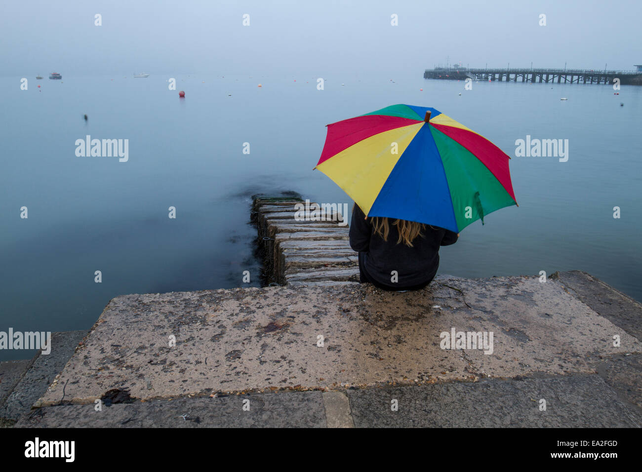 Misty bay with colourful umbrella and female in Swanage Stock Photo - Alamy