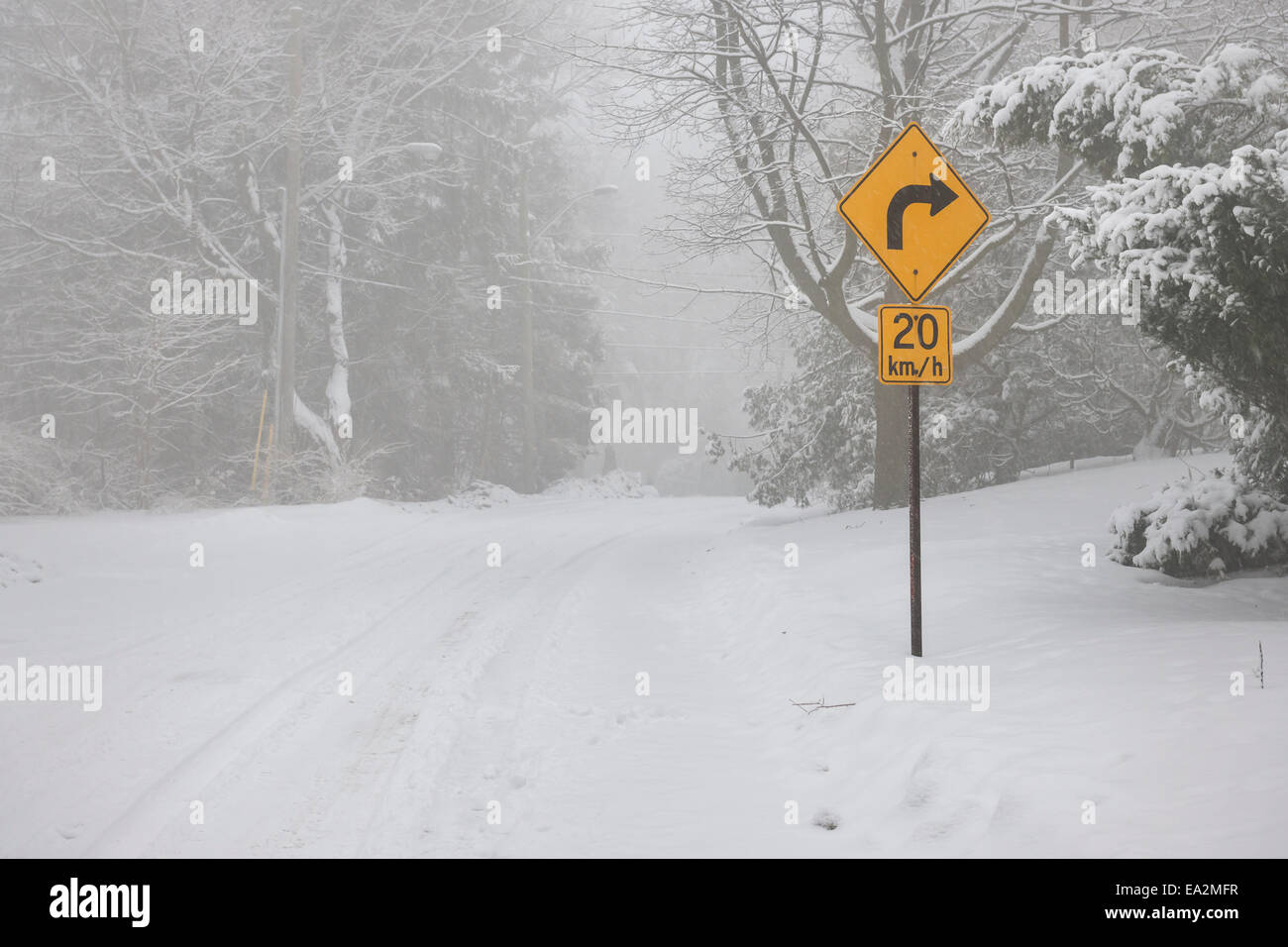 Winter road covered with thick snow and yellow speed limit sign ...