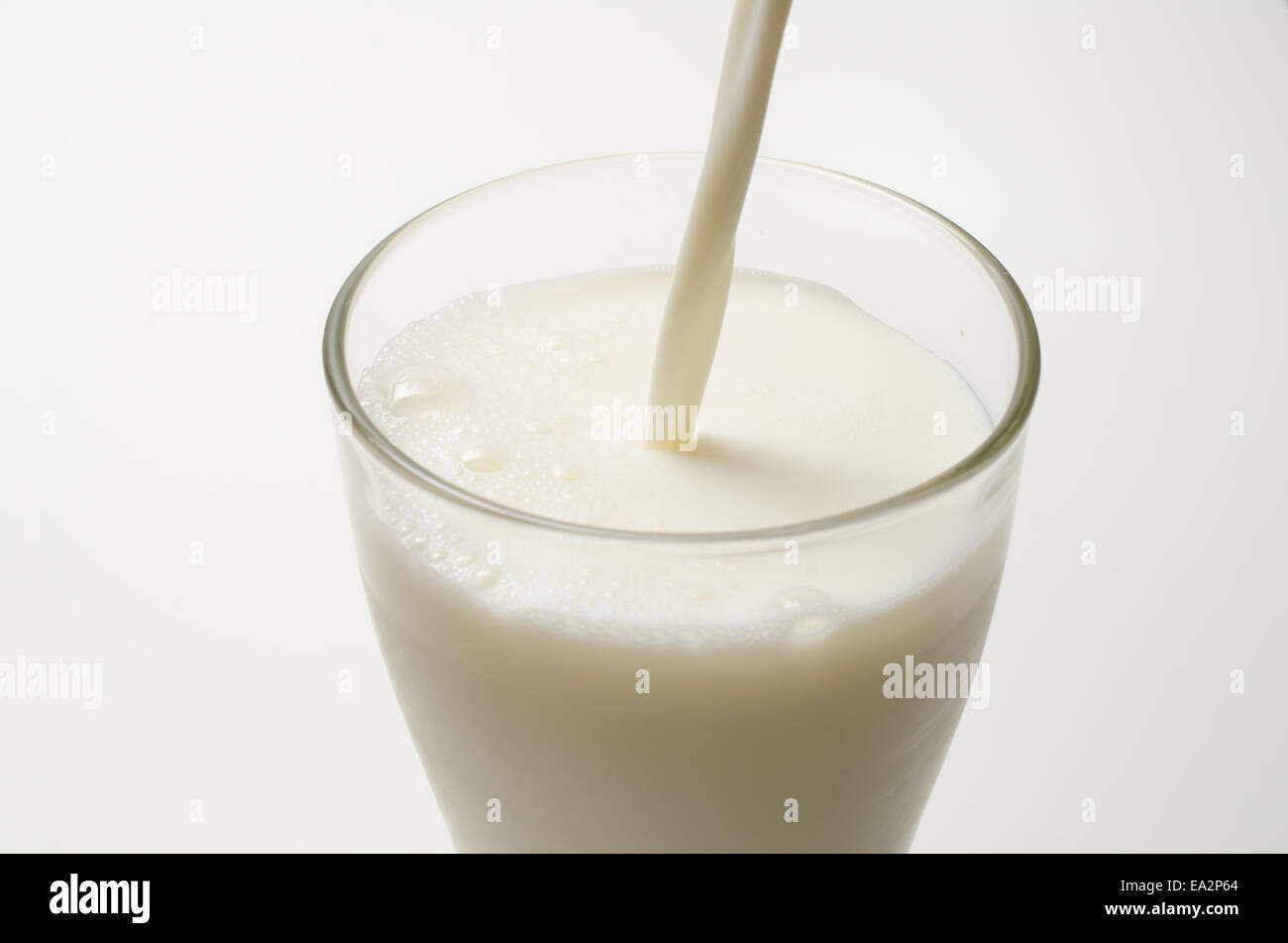 Pouring fresh milk on a white table Stock Photo - Alamy
