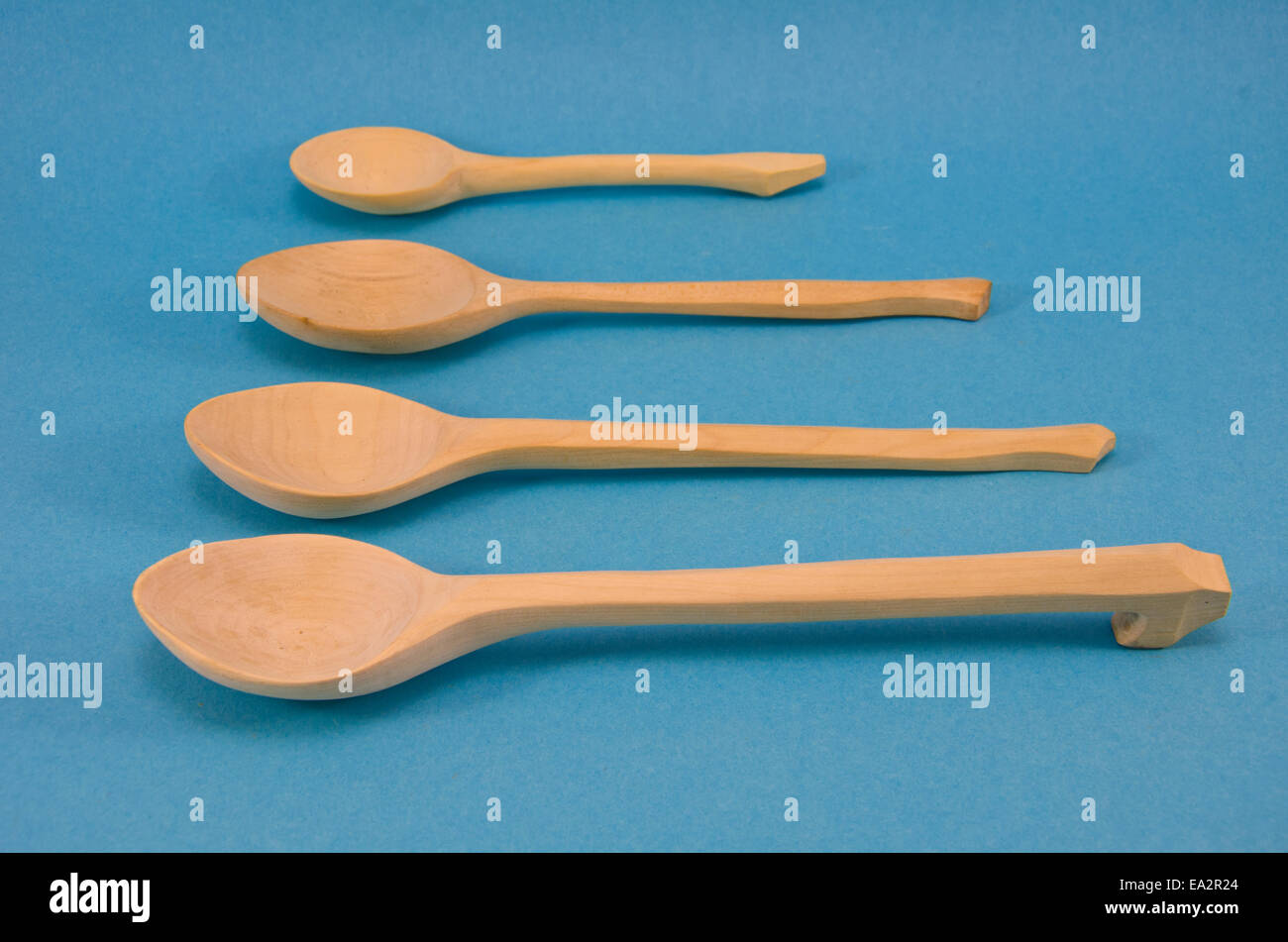 four handmade wooden spoon on blue background Stock Photo - Alamy