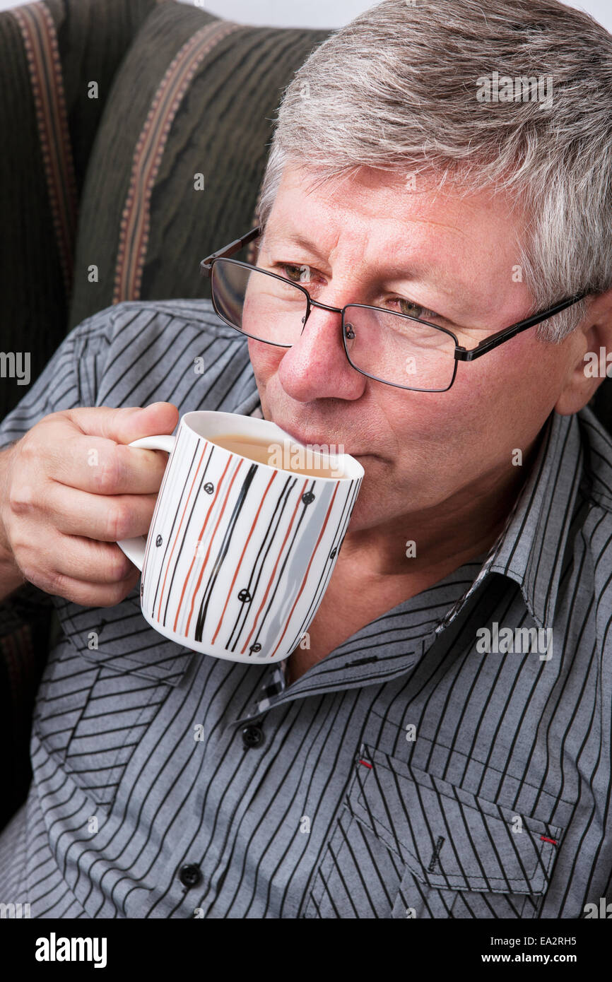 Relaxed adult man drinking coffee at home sitting on couch Stock Photo ...