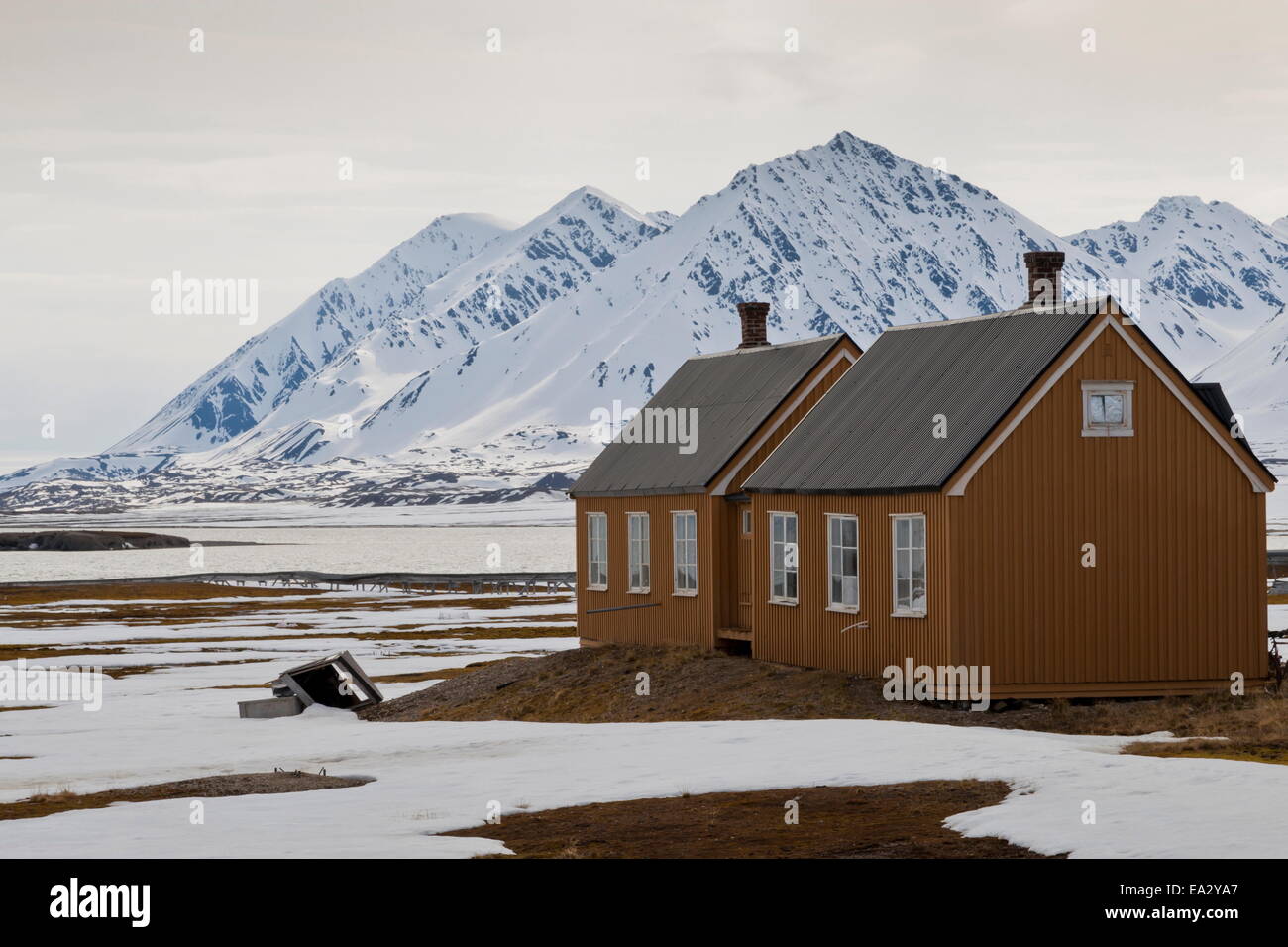 Wooden buildings with snowy mountains behind, Ny Alesund, Spitsbergen ...