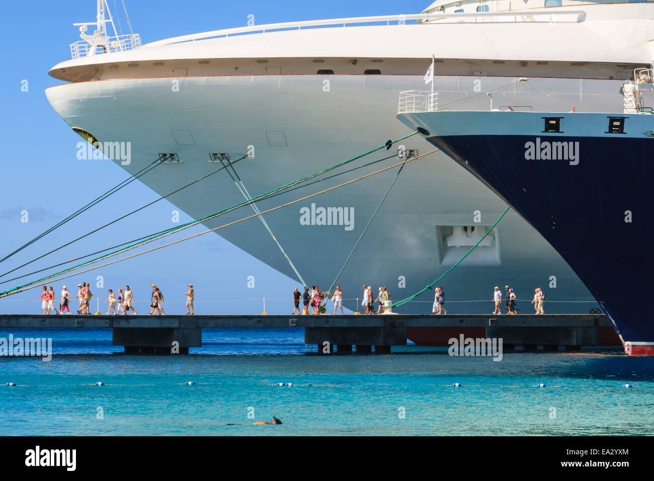 Cruise ships and disembarking passengers, with snorkeler in azure sea ...