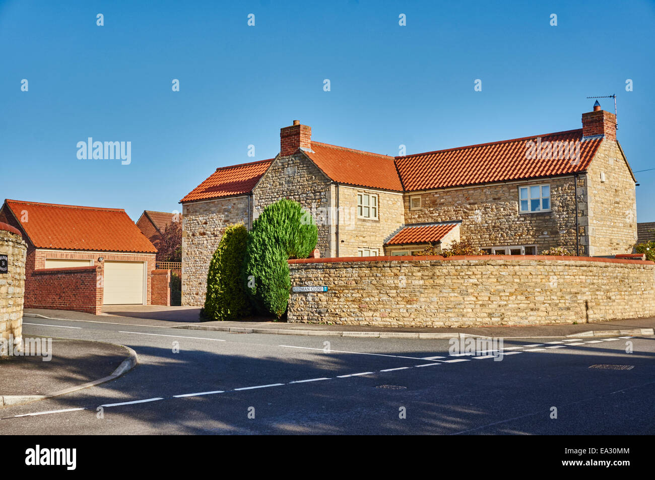 Modern stone built house facing the sun against a clear, blue sky in ...