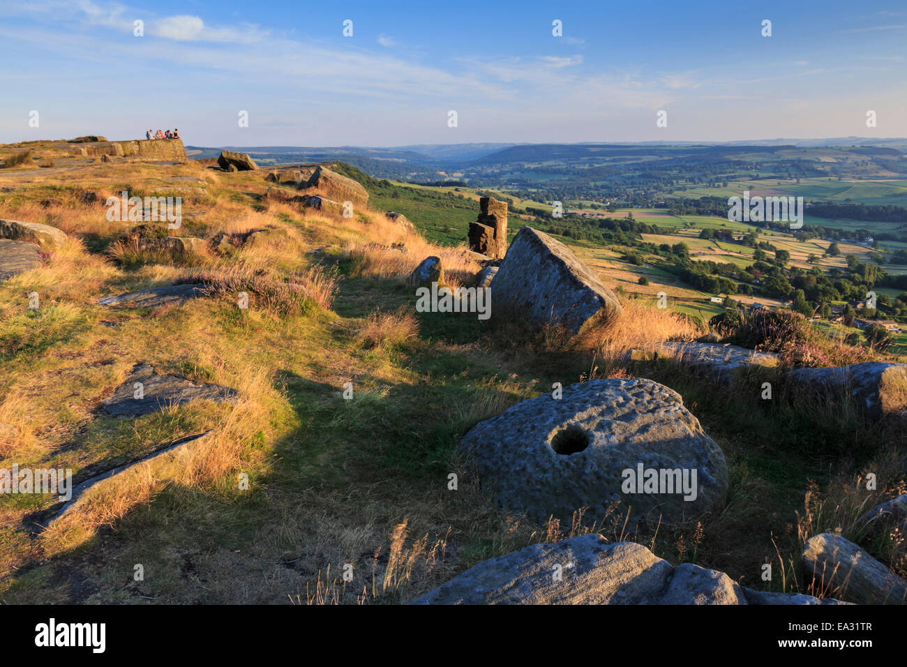 Friends on Curbar Edge with boulders and a millstone in summer, Peak ...