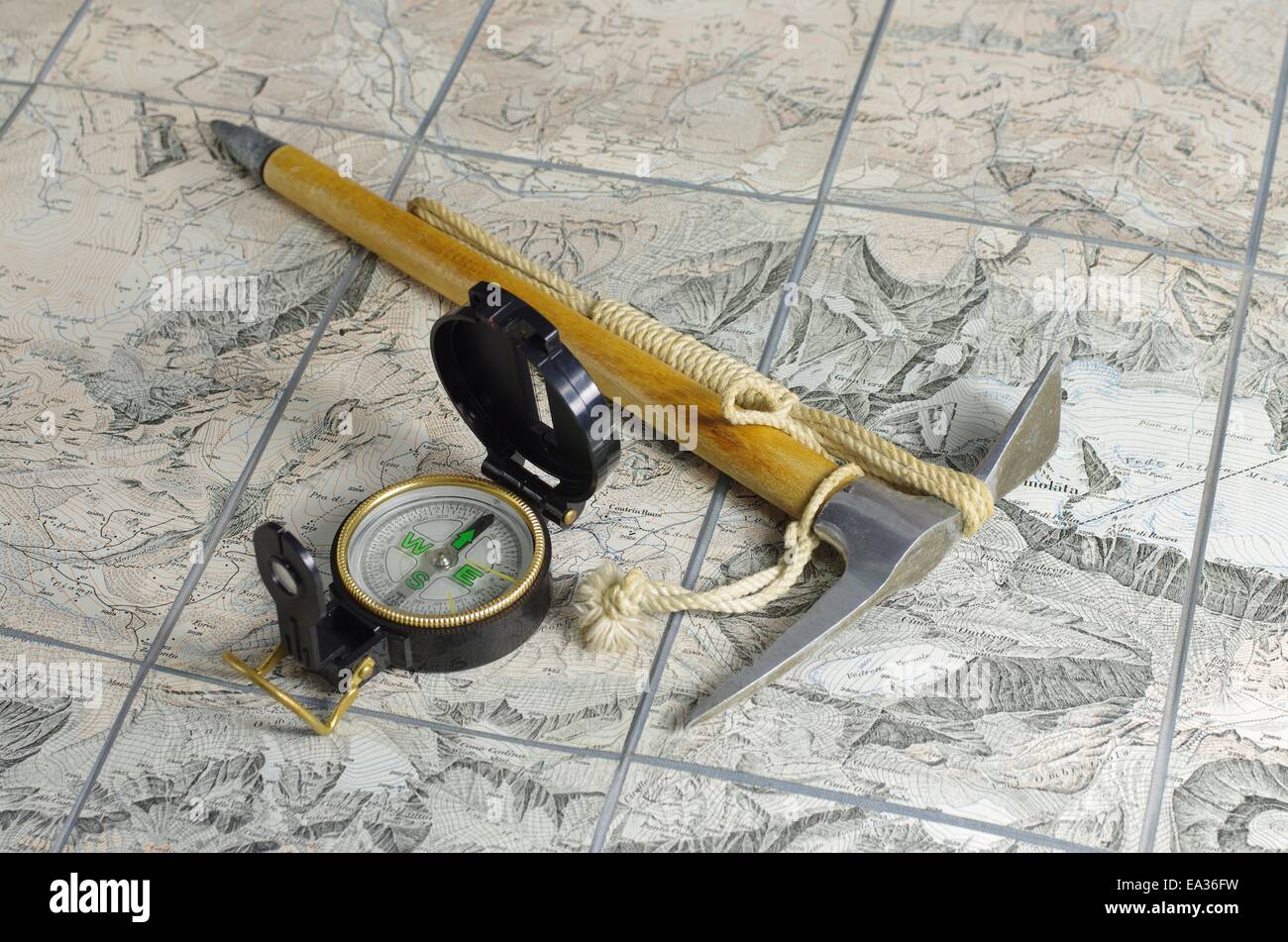 the ice - axe and compass on background of map of mountains Stock Photo ...