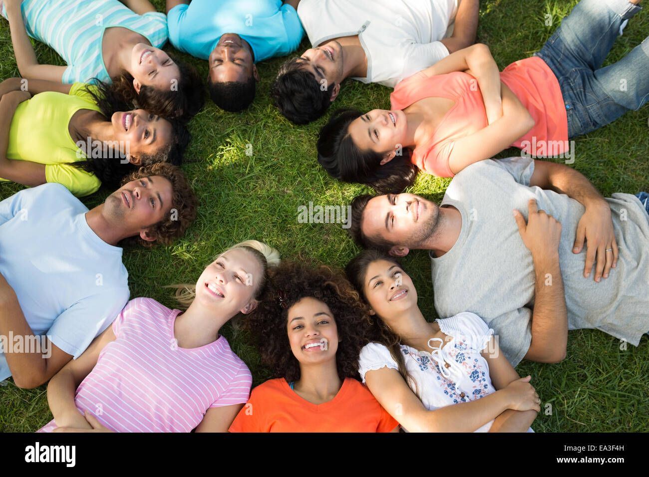 Multiethnic friends lying down in park Stock Photo - Alamy