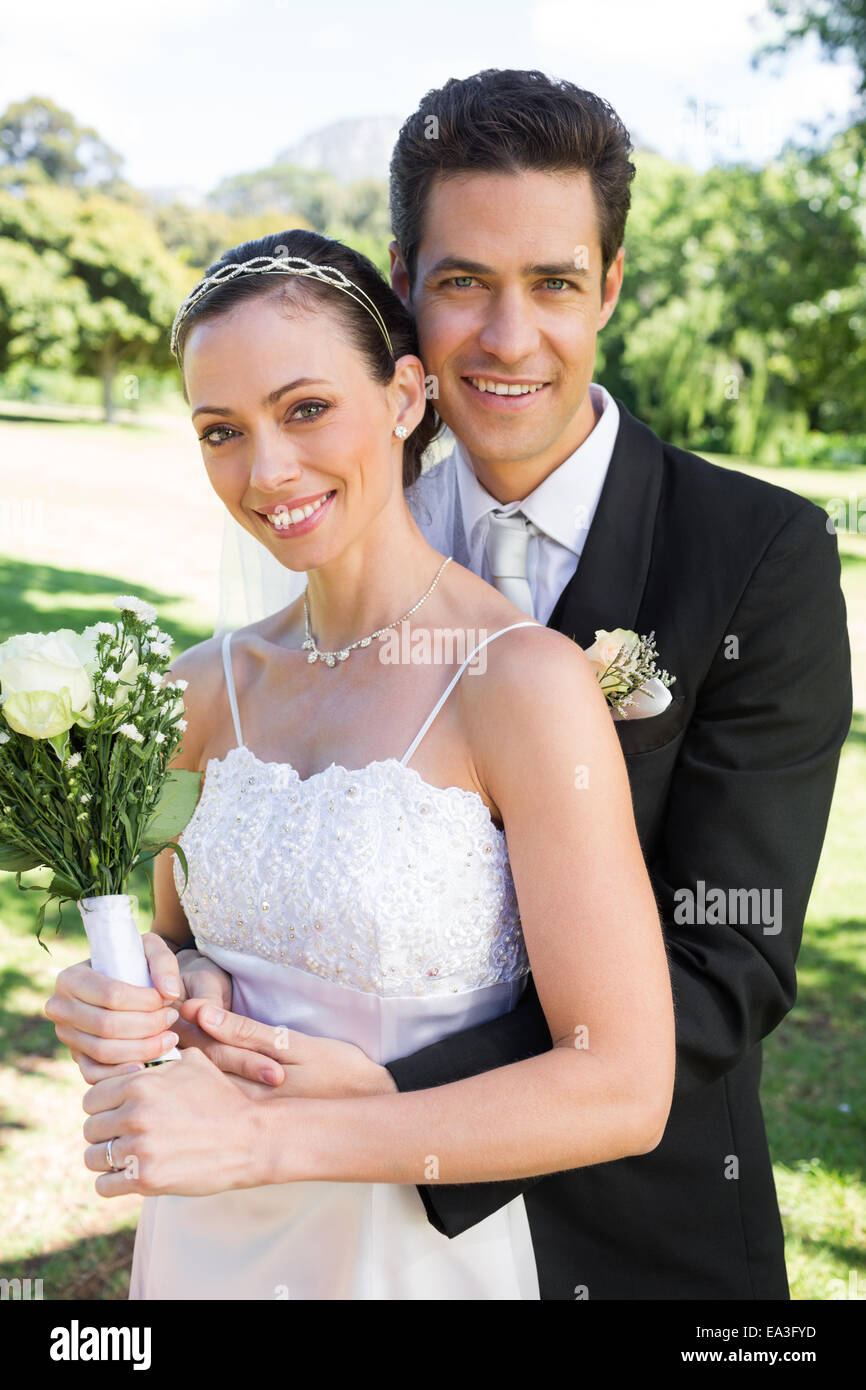 Groom hugging bride from behind in park Stock Photo - Alamy